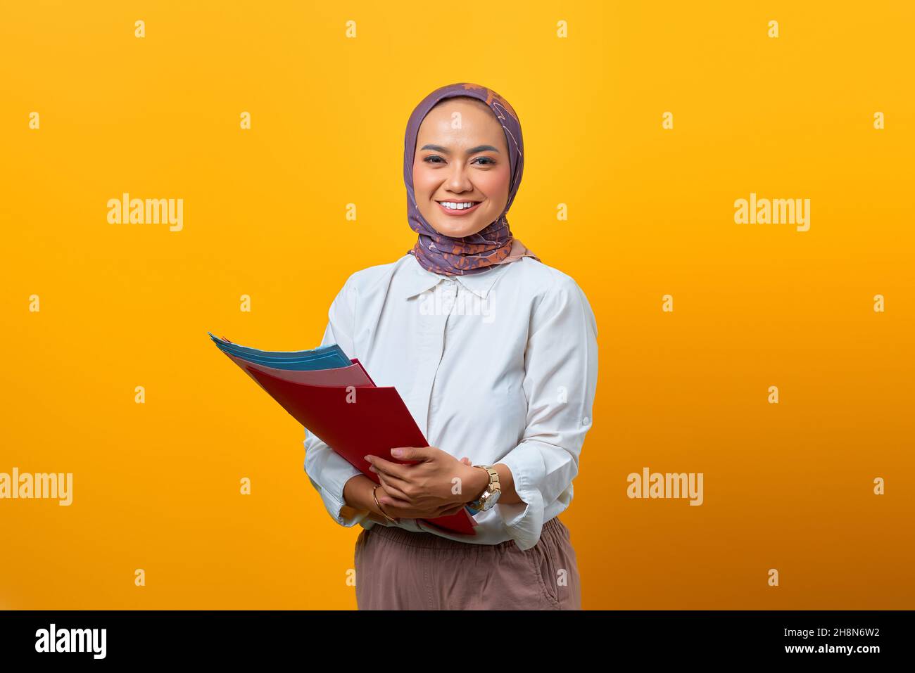 Beautiful Asian woman holding folders while looking at camera with ...