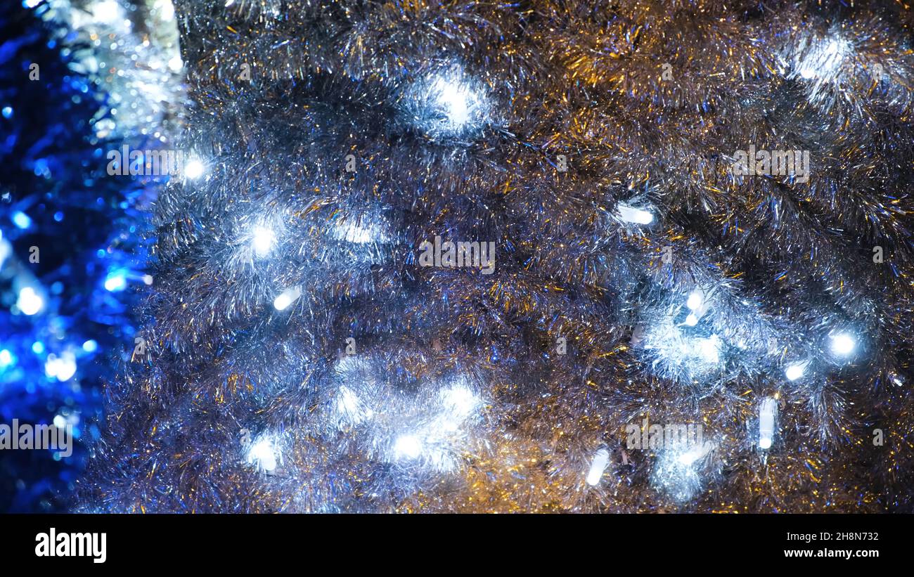 Close-up of tinsel with garland. Concept. Blue garland glows in silvery ...