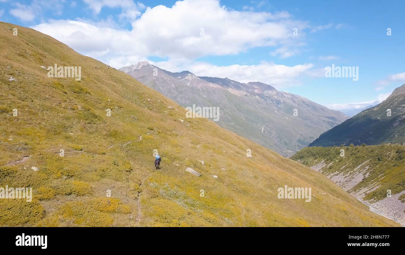 Top view of man riding horse in mountains. Clip. Mountain landscape ...