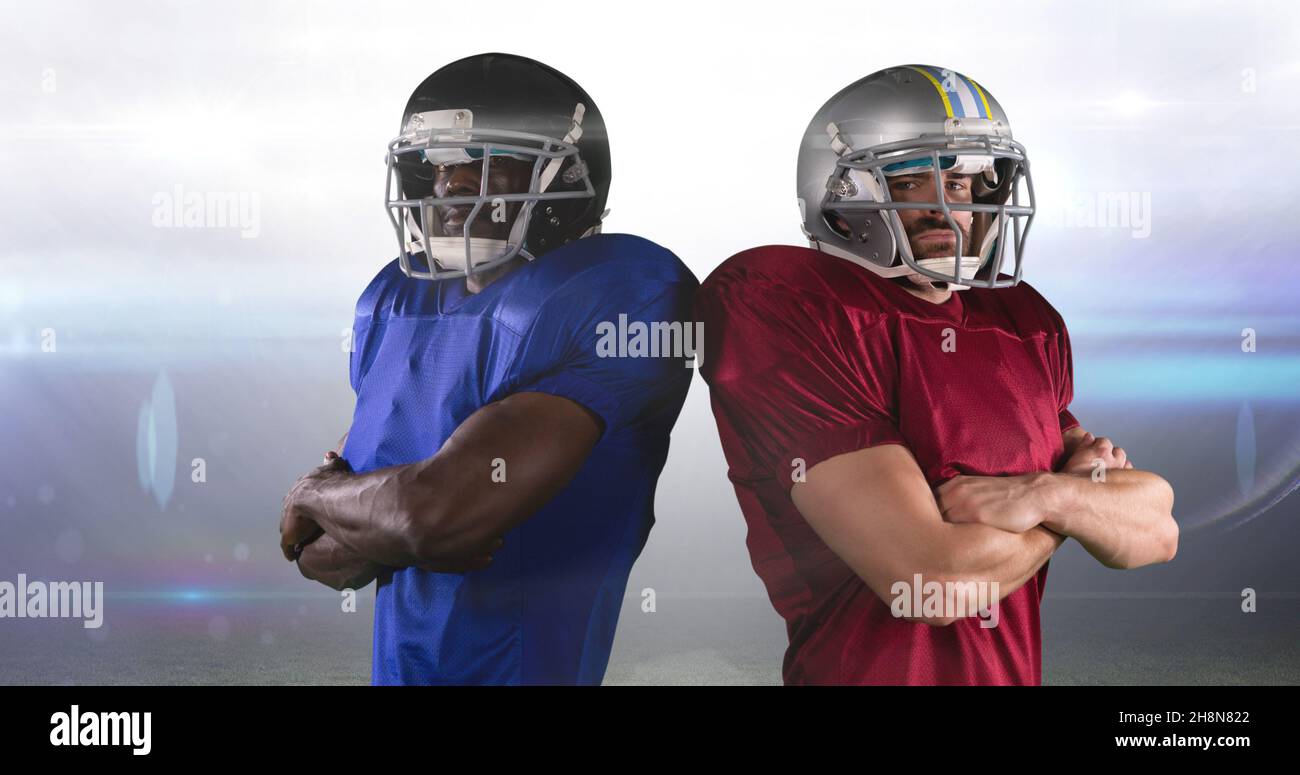 Portrait of rival american footballers standing back to back with arms ...