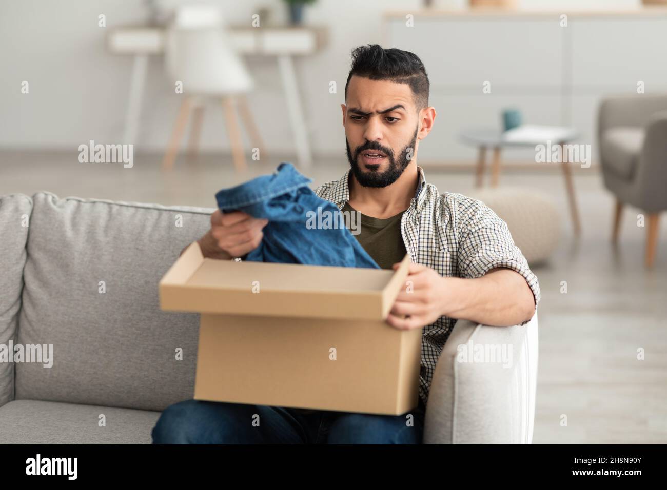 Bad delivery service. Angry Arab man unpacking cardboard box, receiving ...
