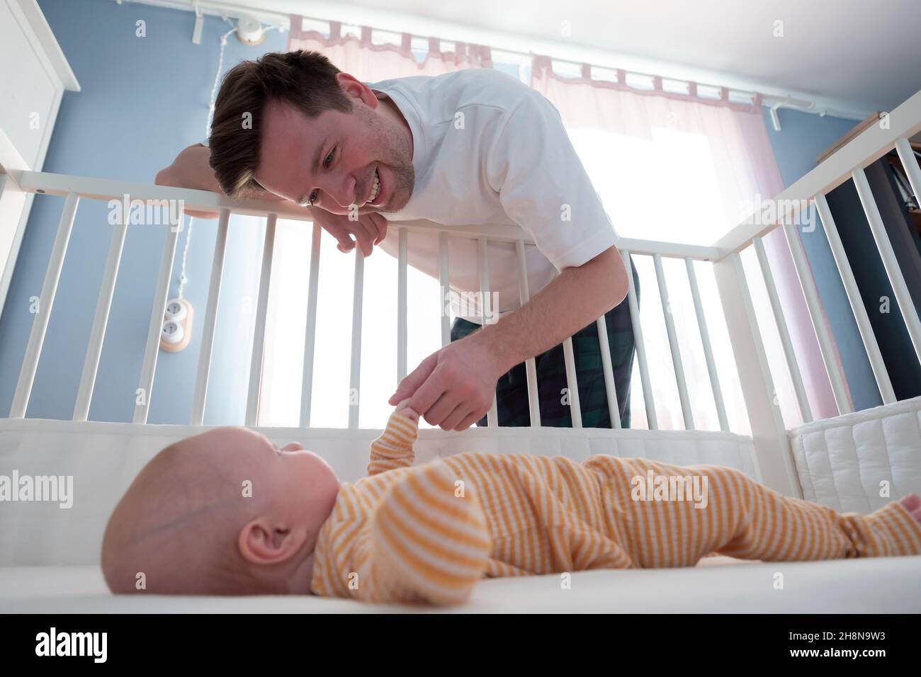 Young man playing with his little baby in bed Stock Photo - Alamy