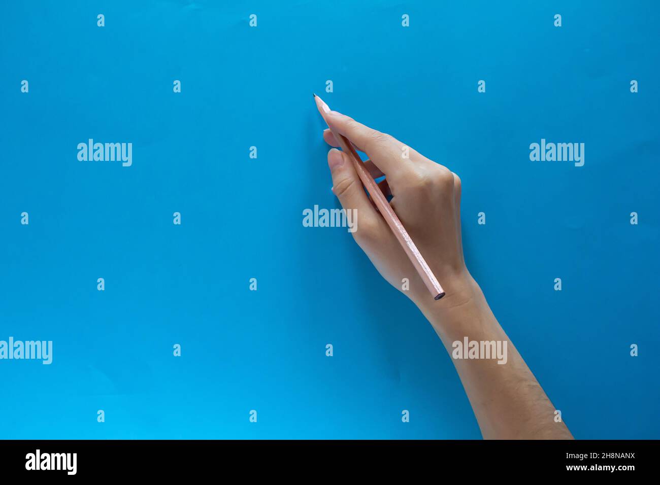 Top view hand holding wooden pencil isolated on blue background ...
