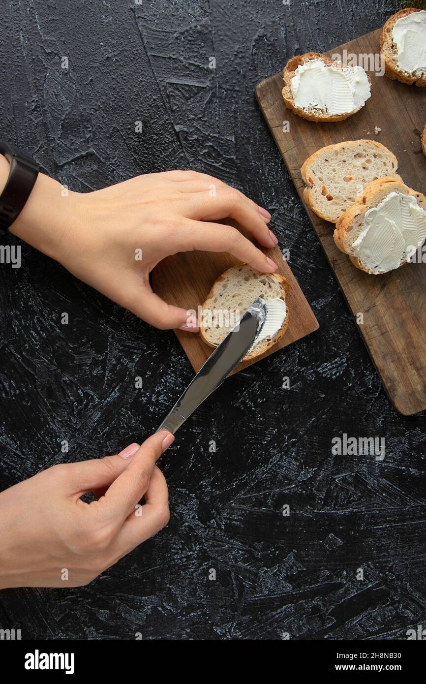 the process of making sandwiches or snacks. female hands smear cream ...