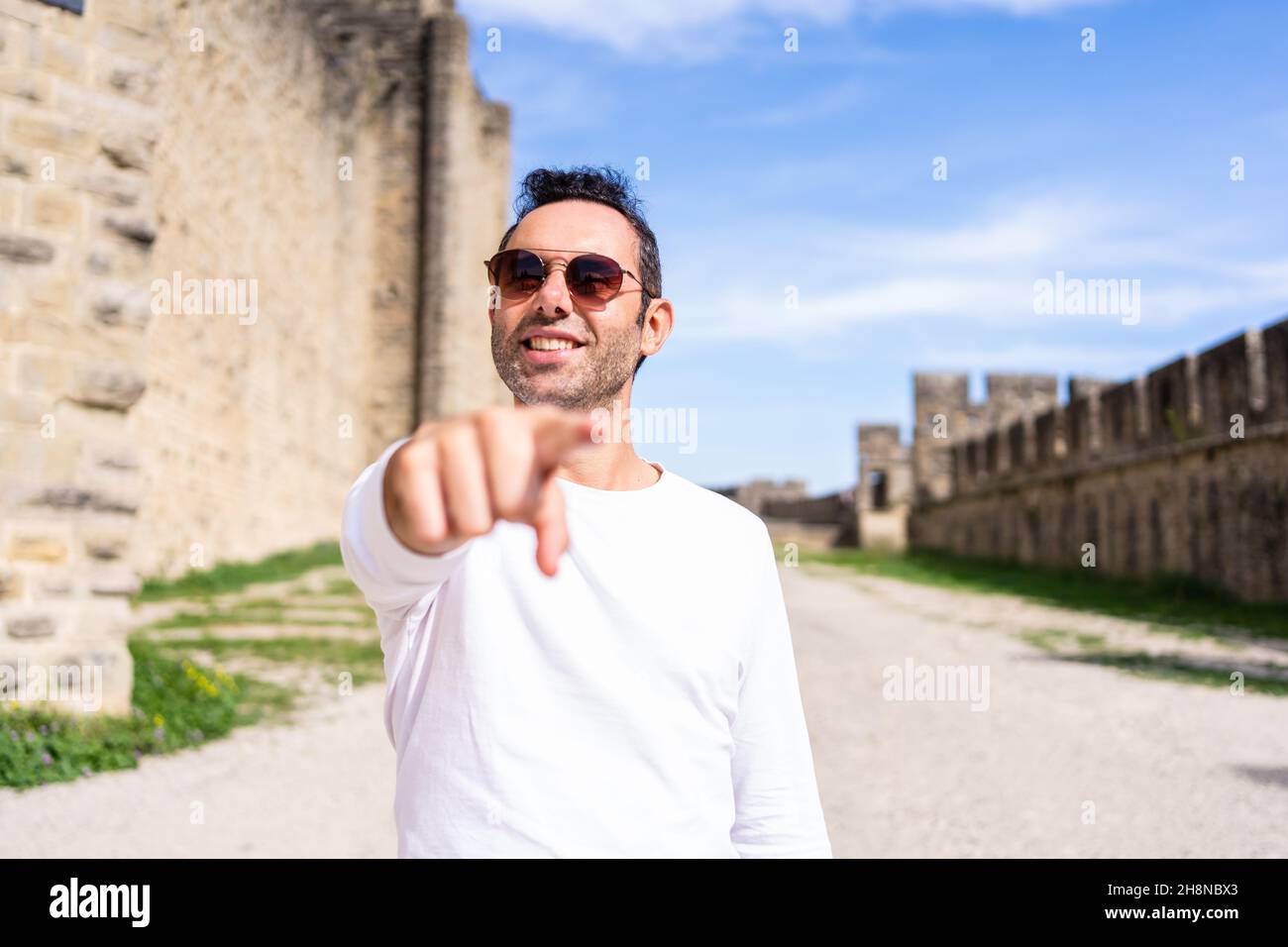 Man with sunglasses pointing forward while standing next to a medieval ...