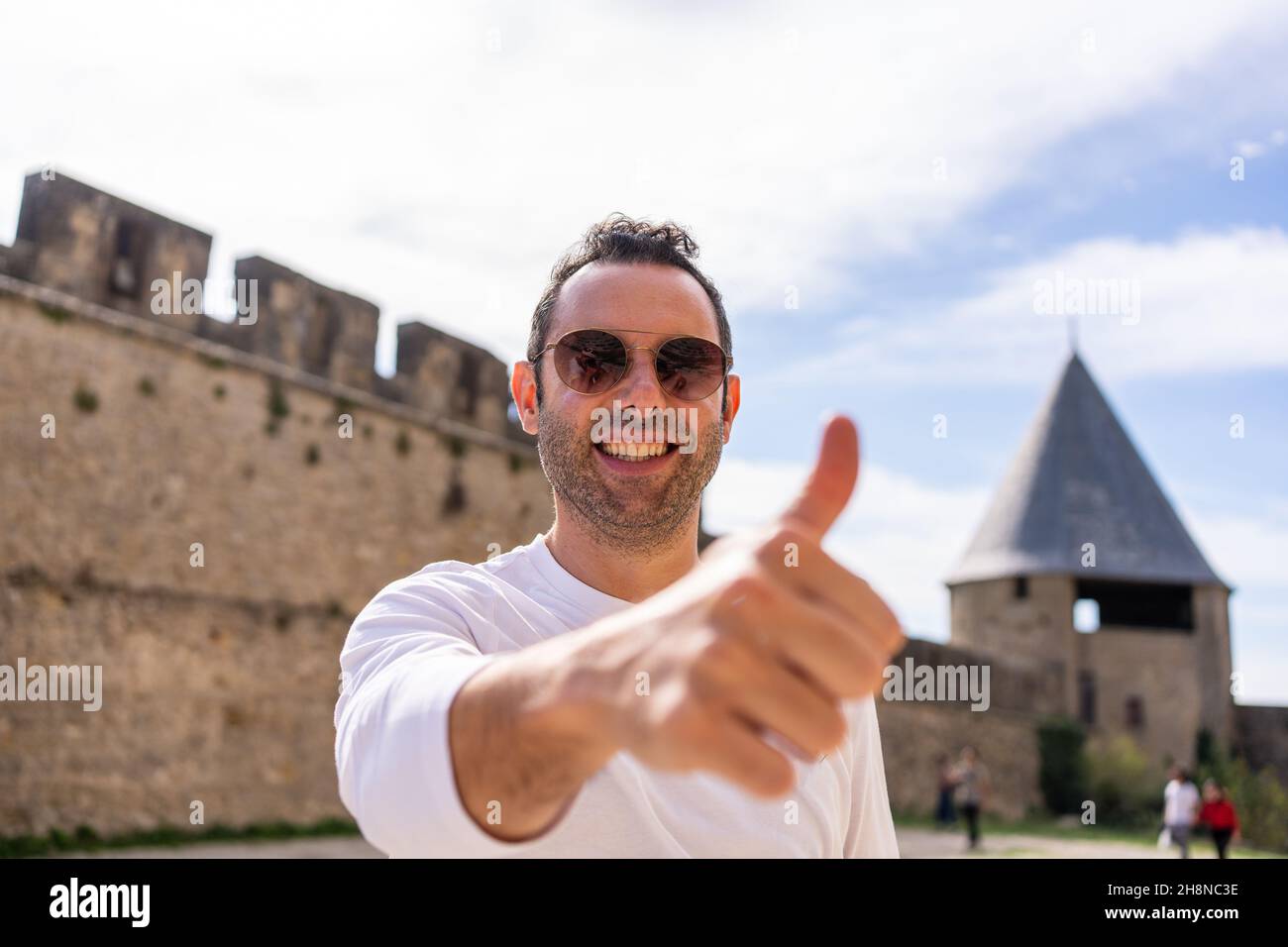 Man gesturing to be okay with the finger standing on a medieval castle ...