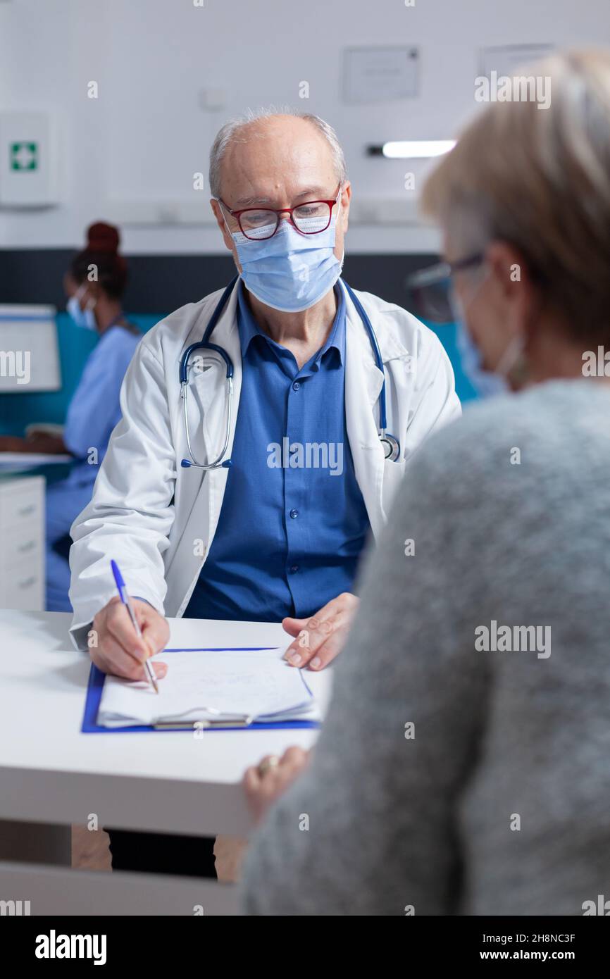 Specialist taking notes on clipboard papers while doing consultation ...