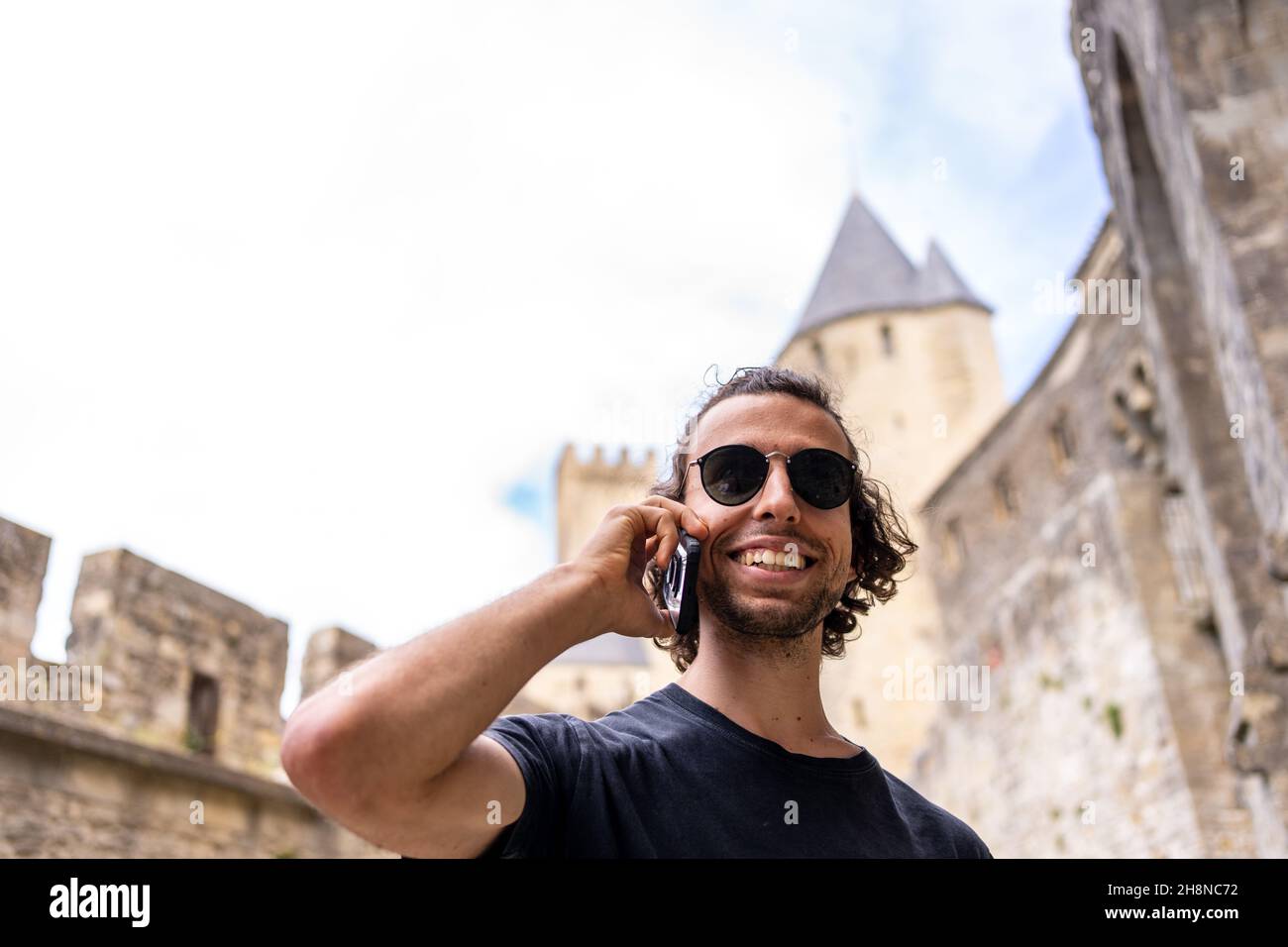 Young adult caucasian man talking with a mobile in a medieval castle ...