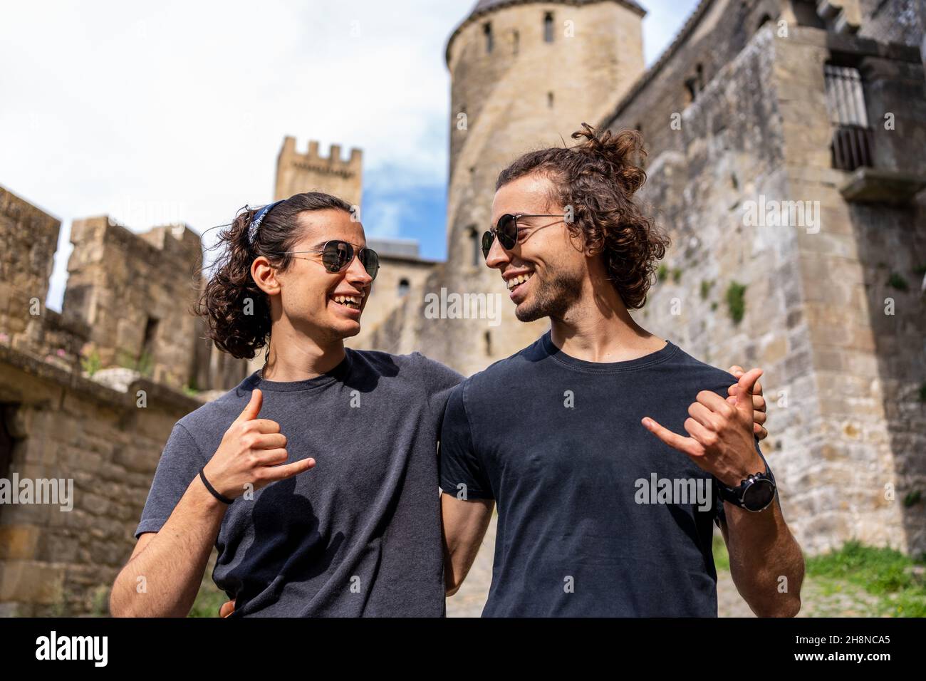 Two friends embracing while gesturing to be cool in a medieval castle ...
