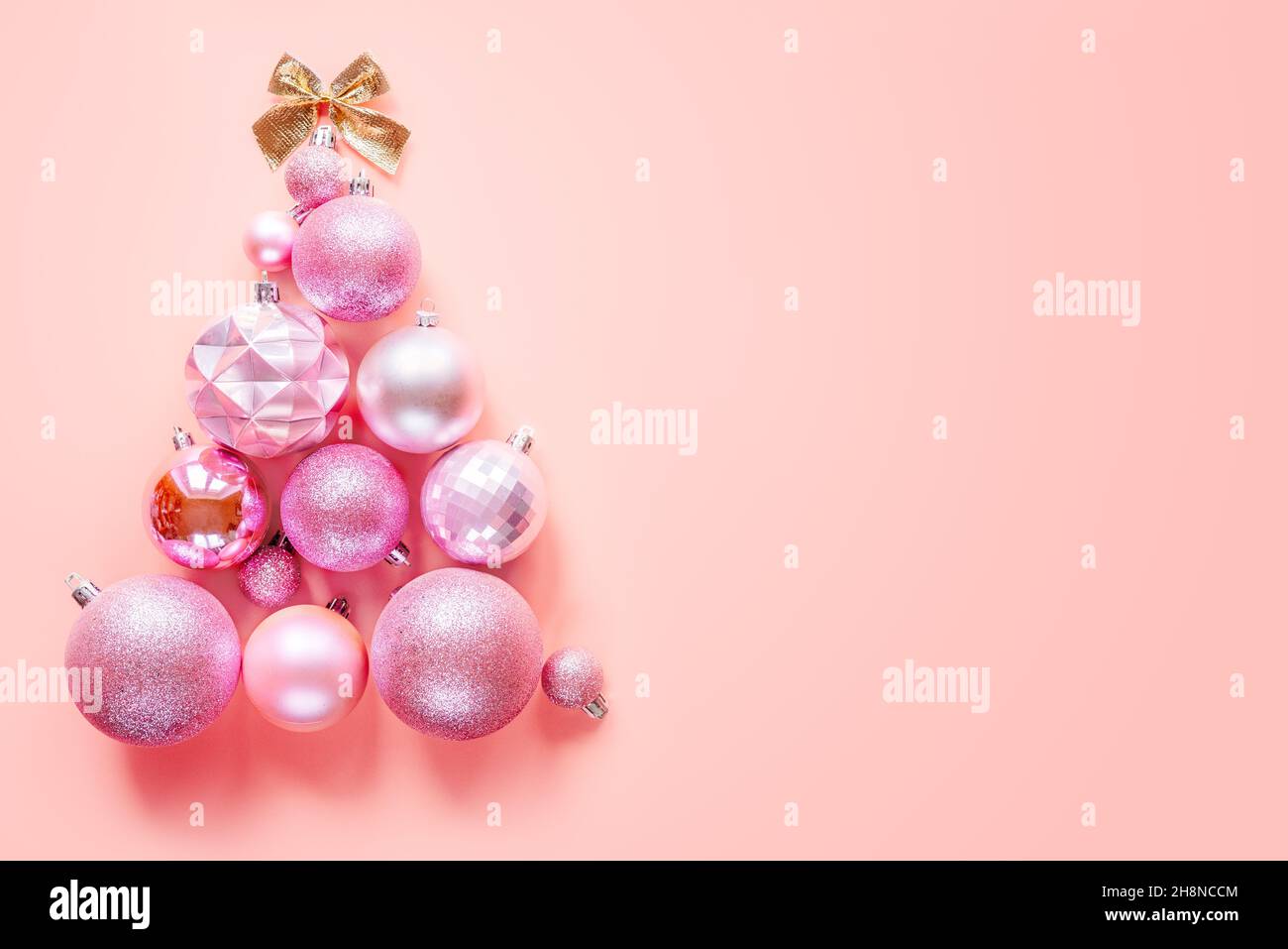 Christmas tree made of pink balls and golden bow on pink background ...