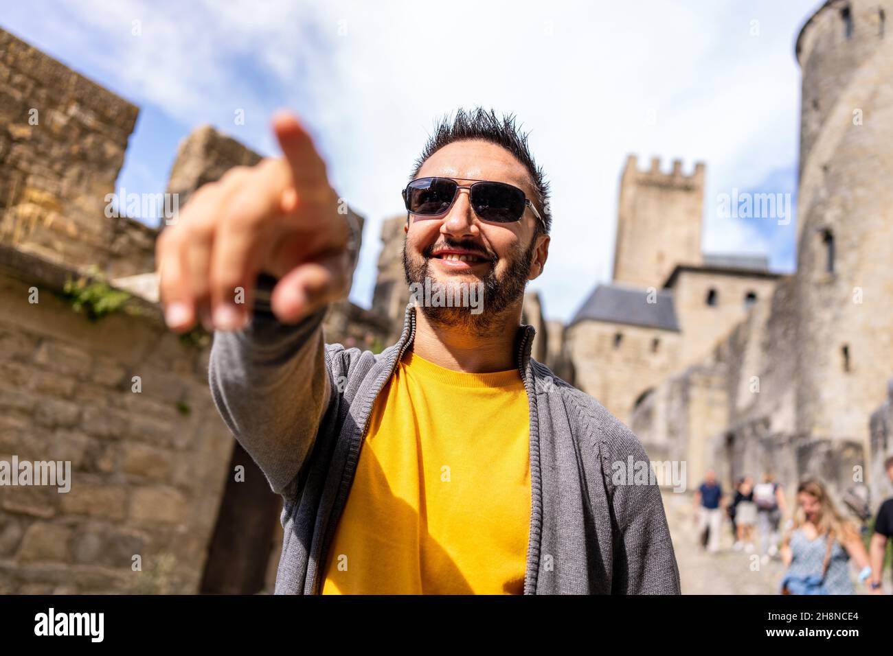 Photo with focus on a man pointing forward standing next to a medieval ...