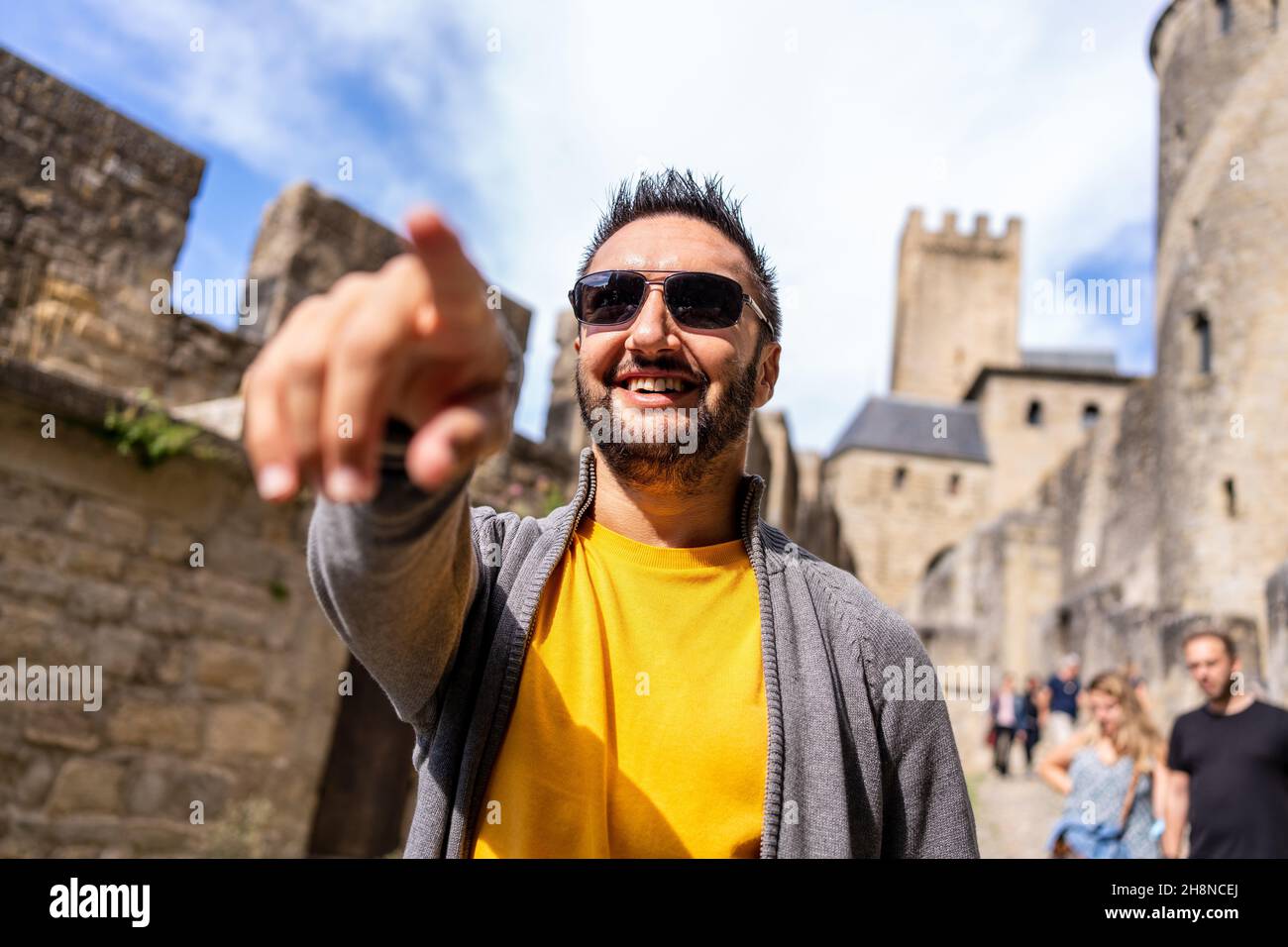Photo with focus on a man pointing forward standing next to a medieval ...