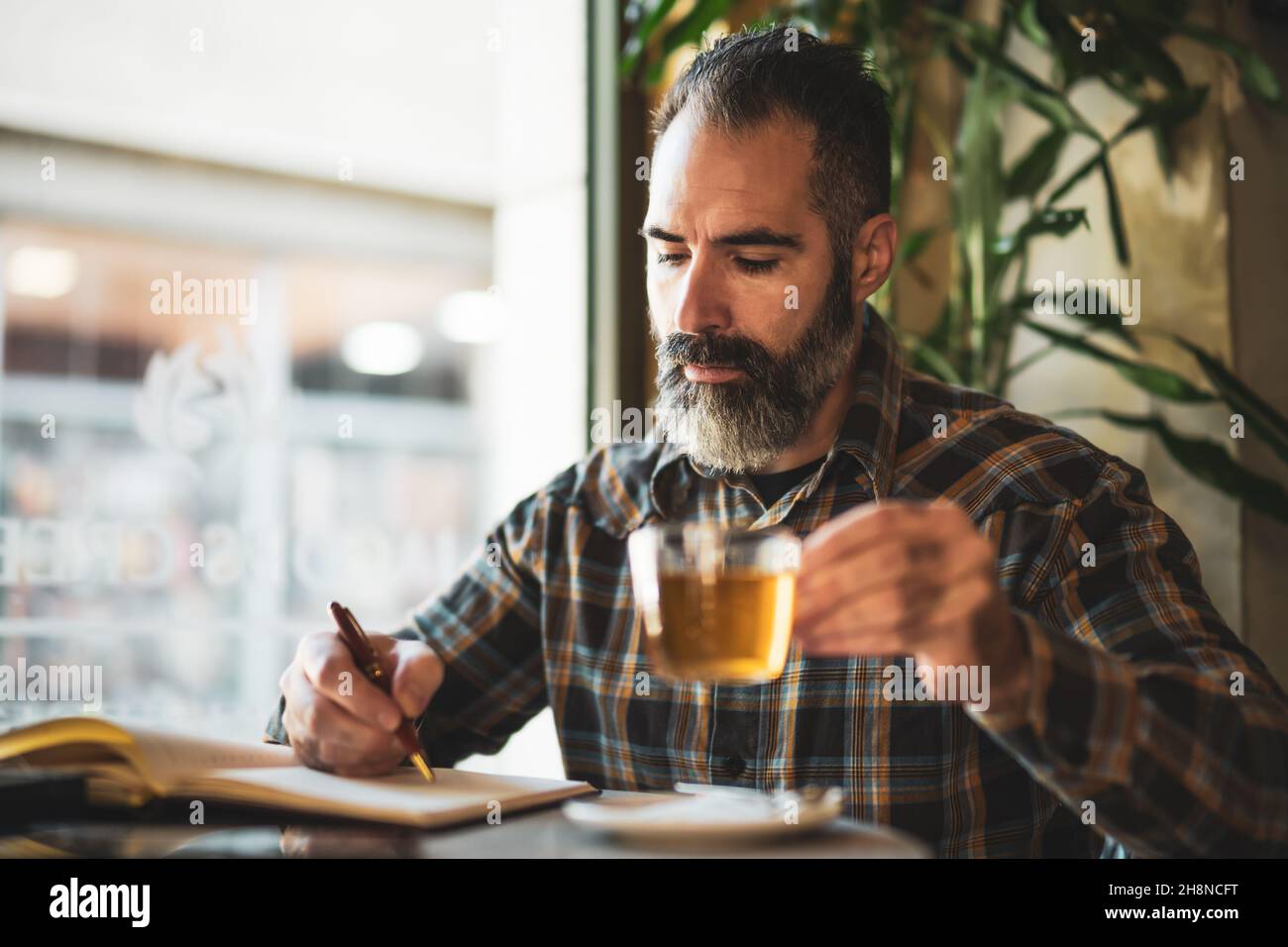 Adult man is sitting in cafe and making his daily schedule. He is ...