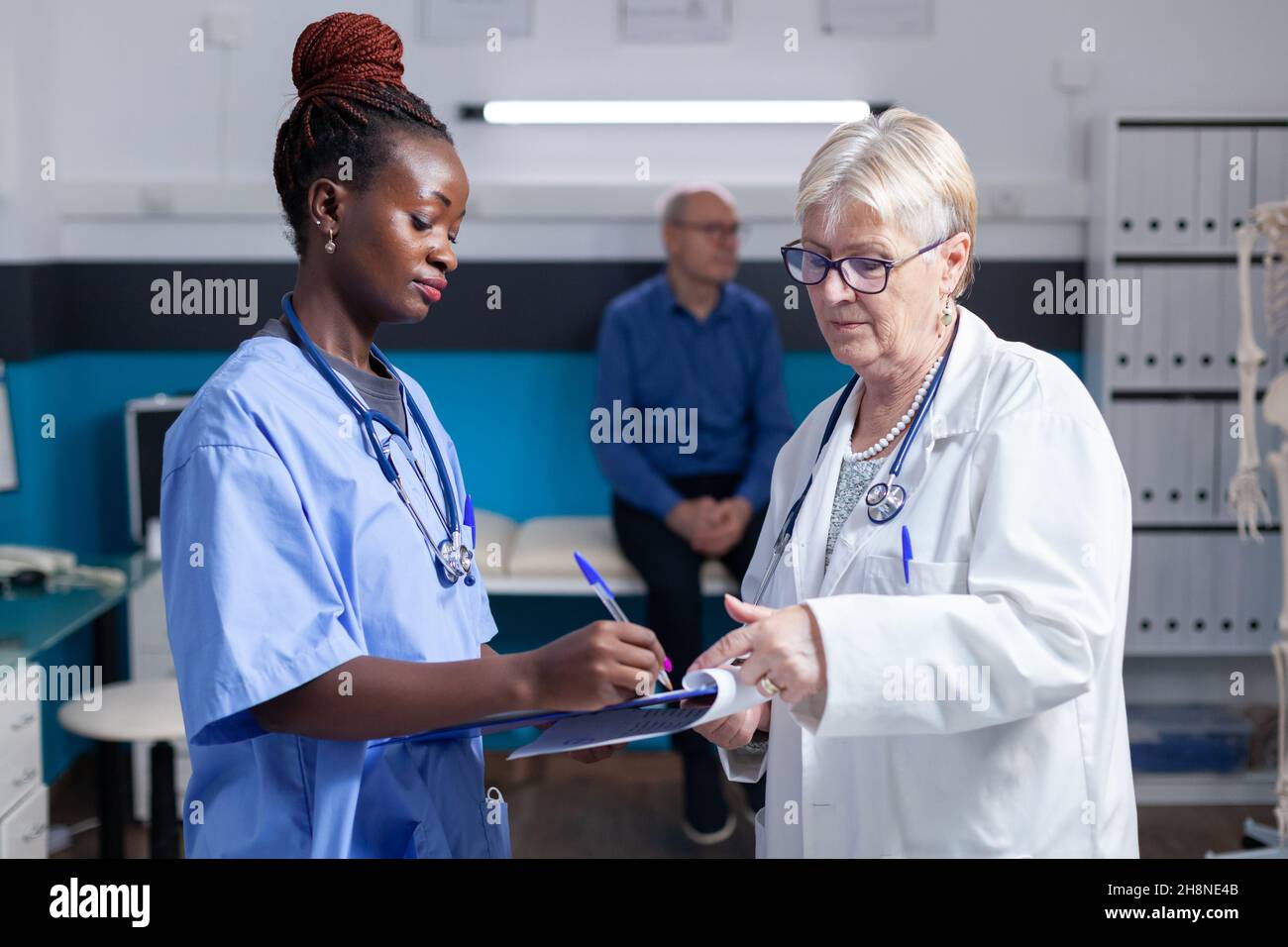 African american nurse signing checkup papers while doctor holding ...