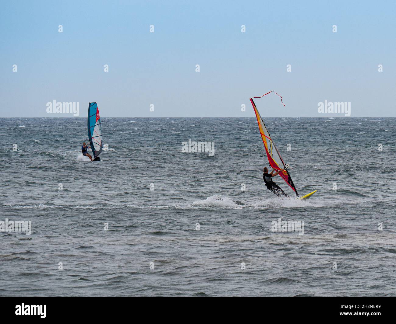 Orange and Blue windsurfing Riding the Waves in a Choppy Sea Stock ...