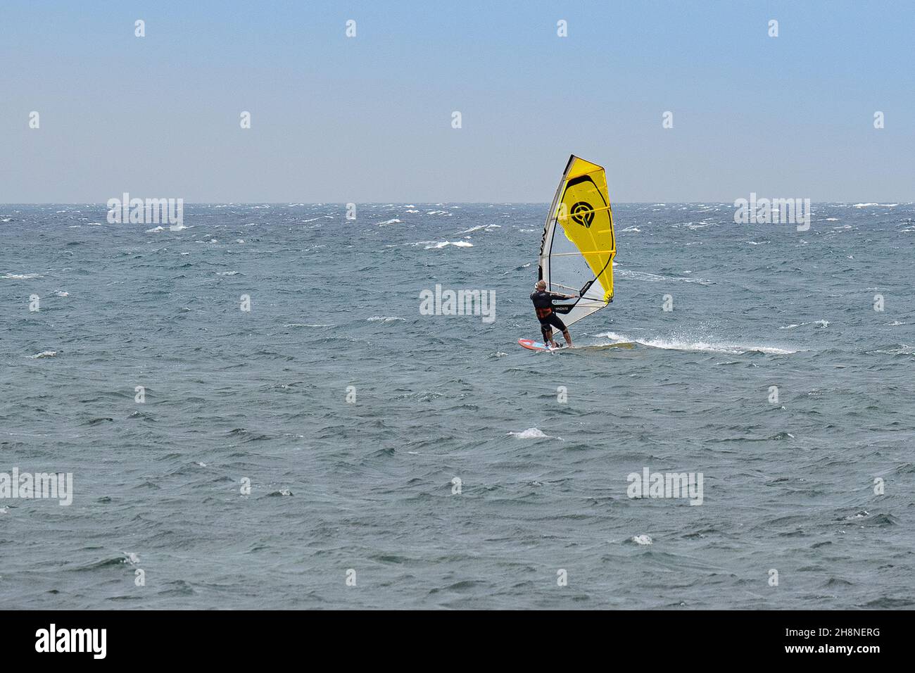 Yellow windsurf Riding the Waves in a Choppy Sea Stock Photo - Alamy