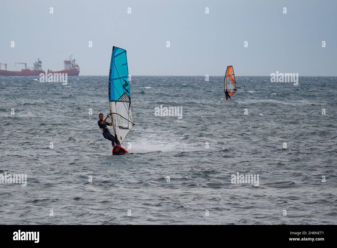 Orange and Blue windsurfing Riding the Waves in a Choppy Sea and Big ...