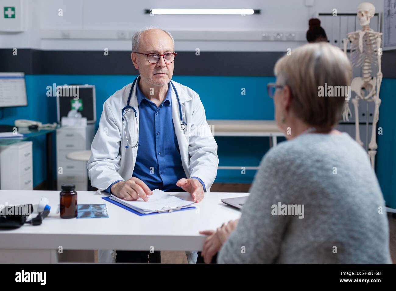 Physician attending consultation appointment with aged patient in ...