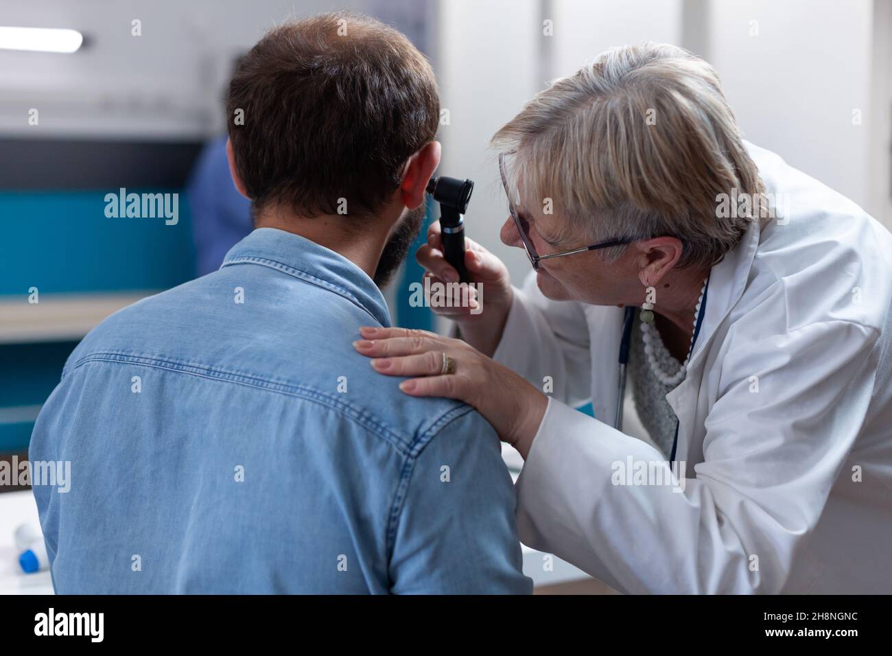 Physician doing ear examination with otoscope for patient in office ...