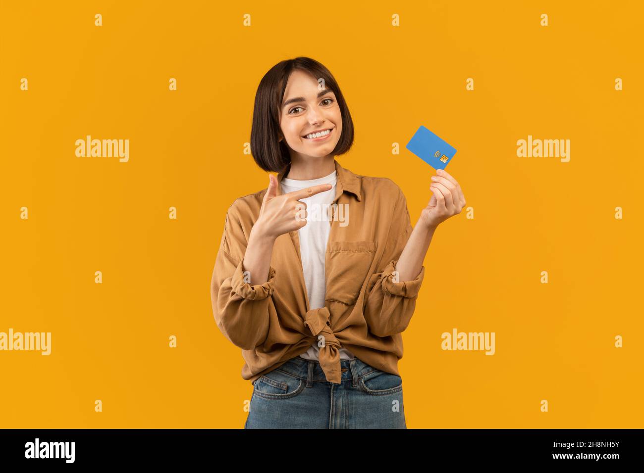 Positive young lady pointing at credit card recommending banking ...