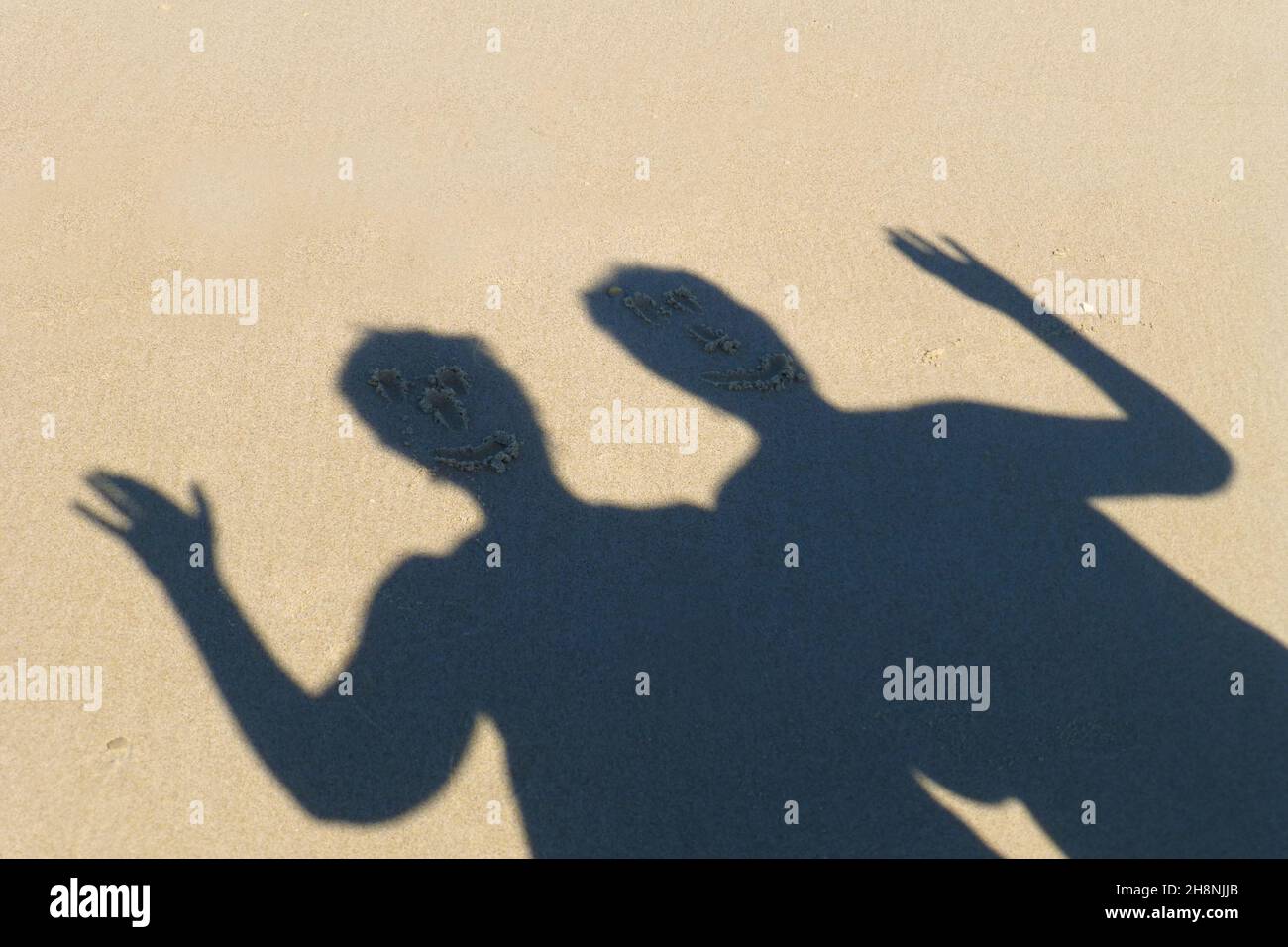 Shadows of two men on the beach sand with faces drawn on it Stock Photo ...