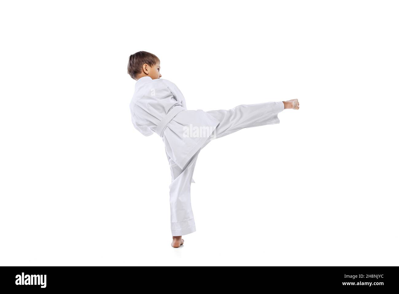 Full-length portrait of little boy, sportsman practising karate side ...