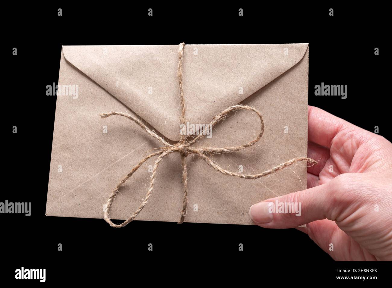 Hand holding closed brown craft envelope tied with twine isolated on ...