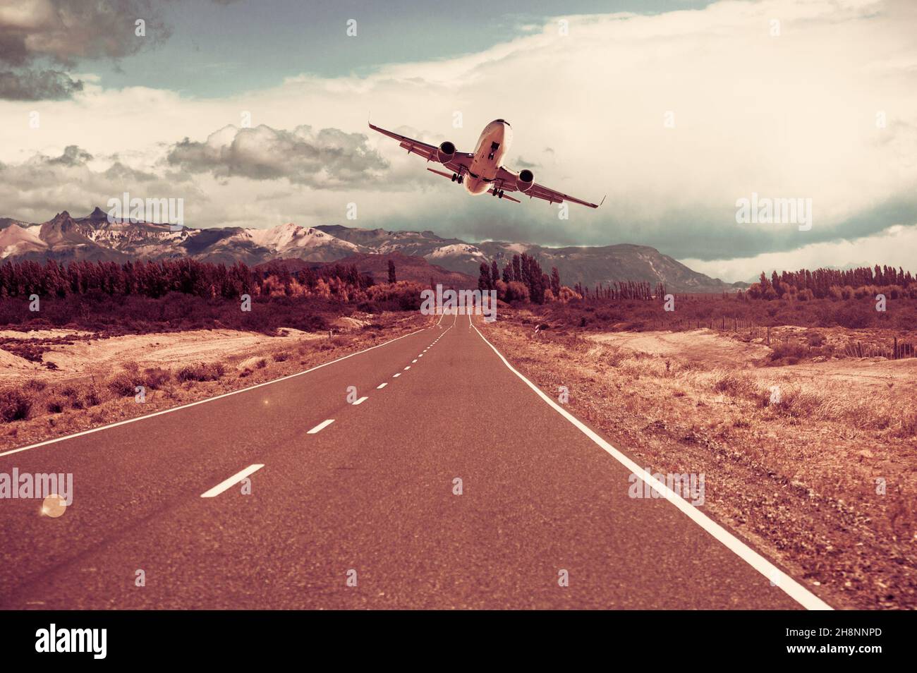 Airplane flying over roadway Stock Photo - Alamy
