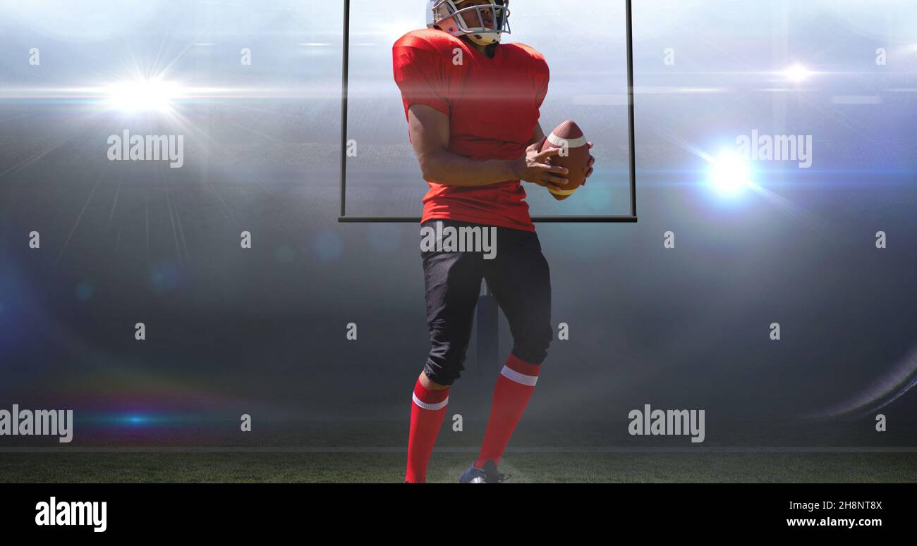 Male american football player holding ball against goal post at ...