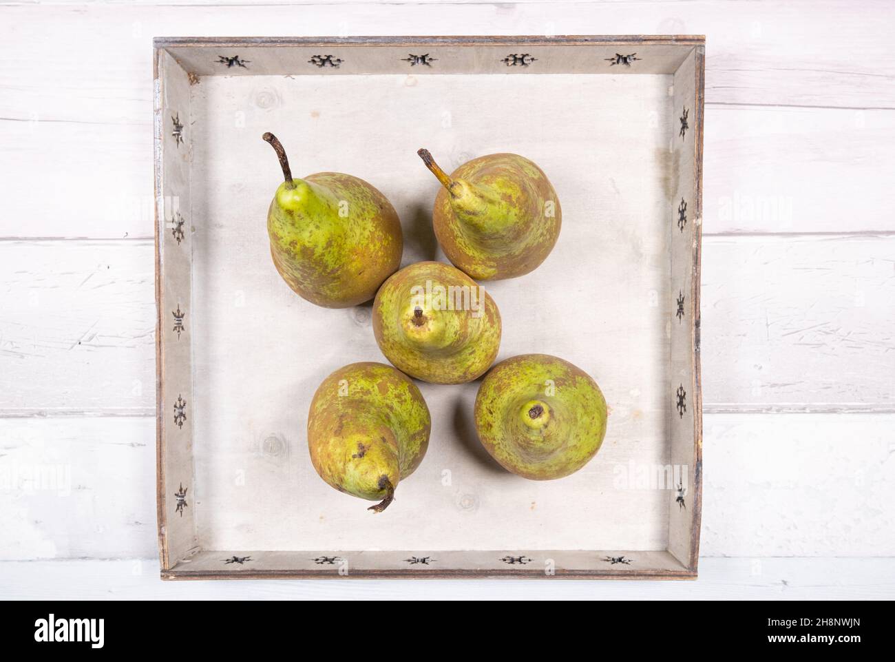 five conference pears placed in an old wooden tray on an old wooden ...
