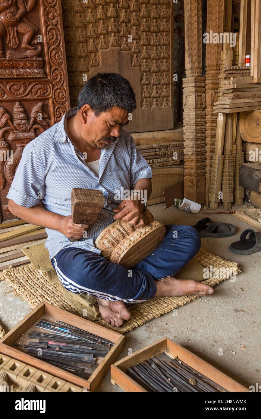 A Nepalese man making a wood carving in his workshop in the medieval ...