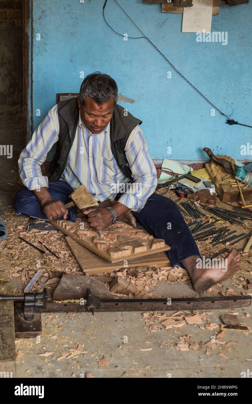 A Nepalese man making a wood carving in his workshop in the medieval ...