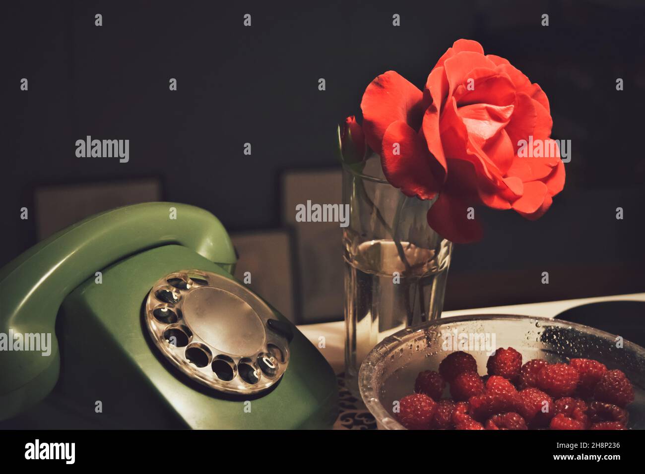 Single red rose in a glass next to the old telephone and a bowl of ...