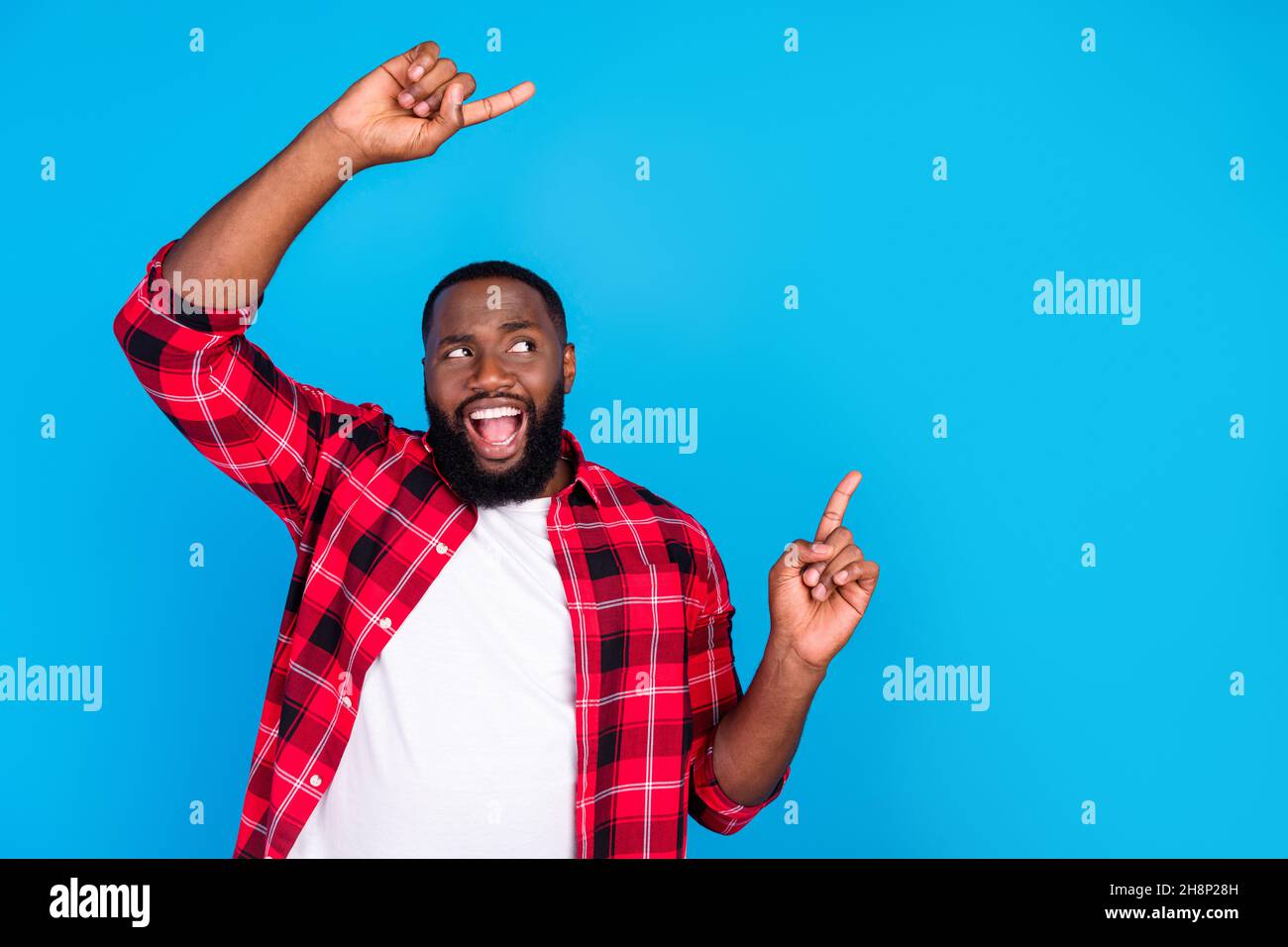 Photo of doubtful happy afro american man point fingers empty space ...