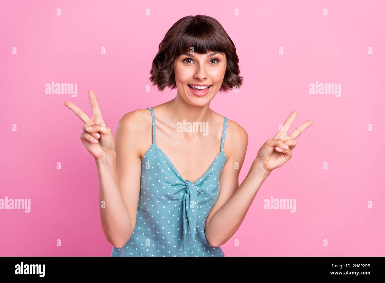 Portrait of attractive cheerful girl showing double v-sign having fun ...