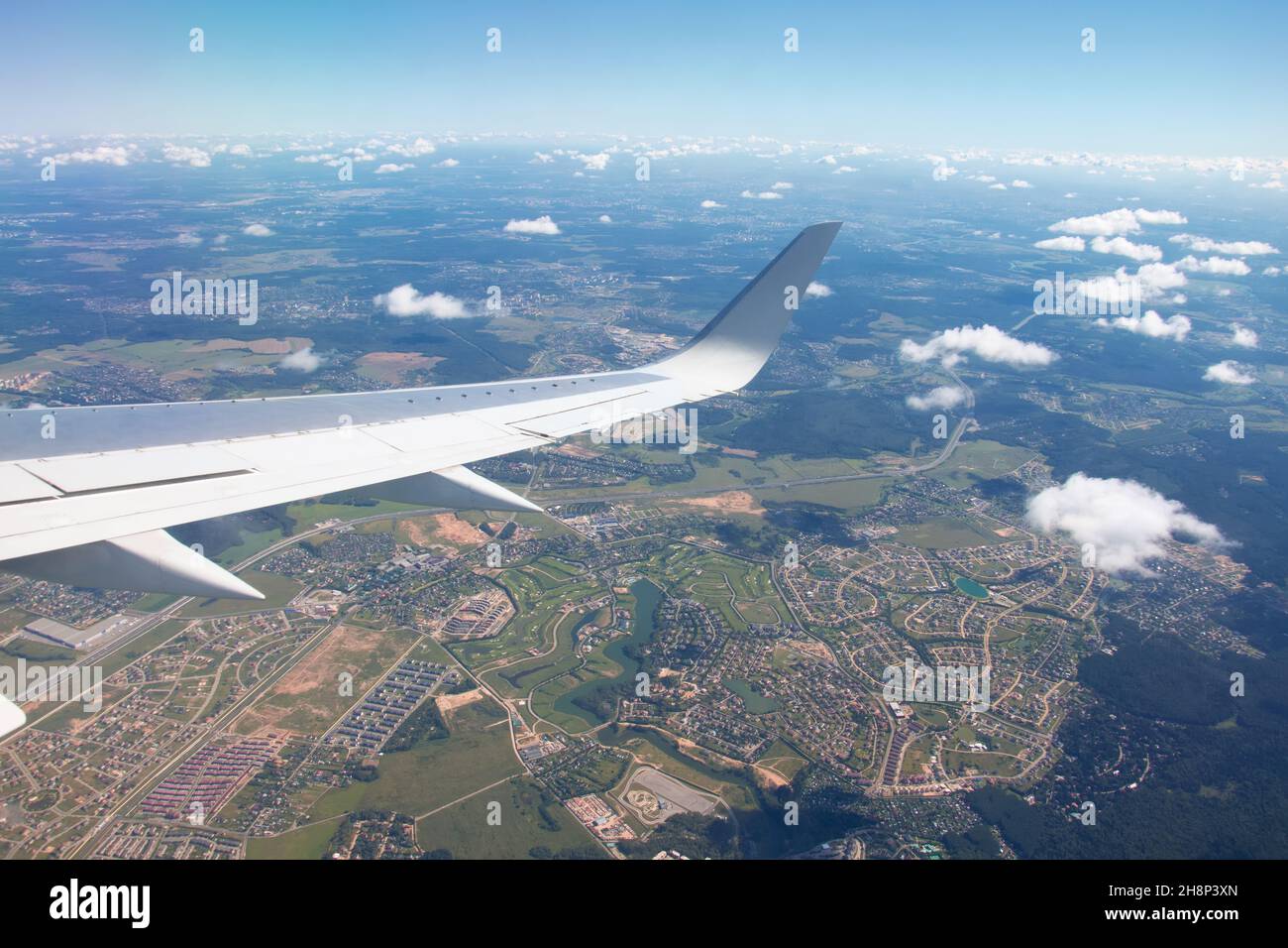 Airplane window view showing wing of the plane flying over small town ...