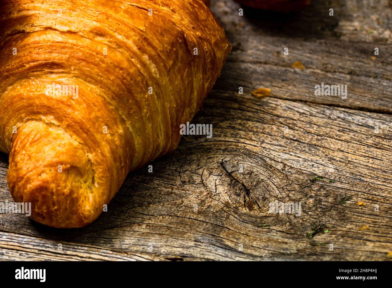 Closeup shot of a delicious and fresh croissant isolated on a wooden ...