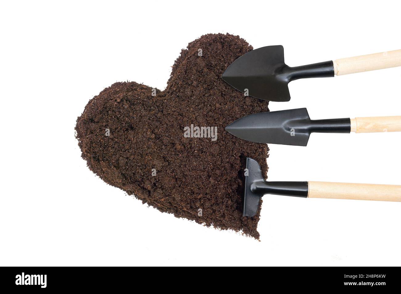 Selection of gardening tools lying in a heart-shaped pile of soil ...