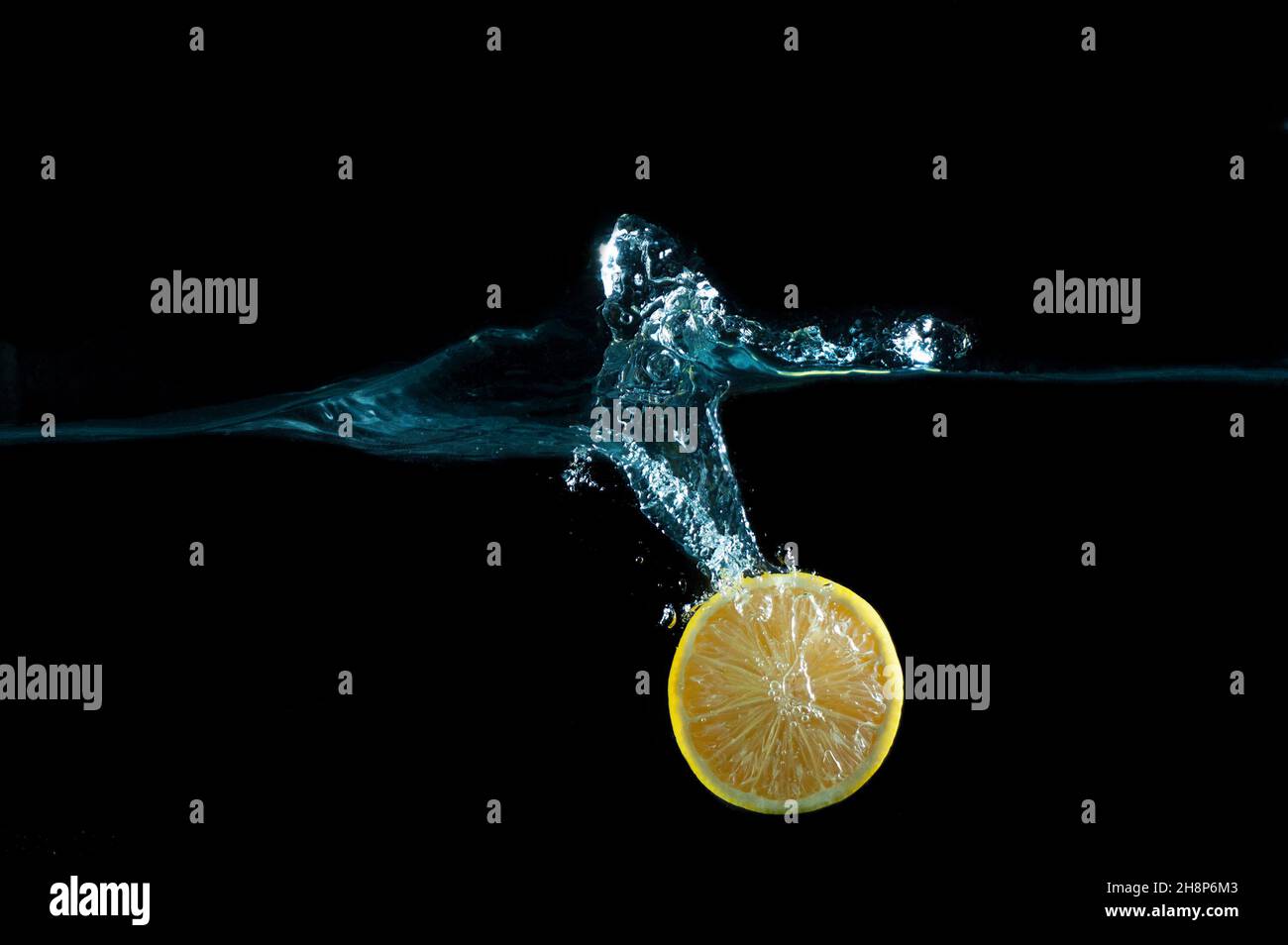 Half of a fresh lemon falling into water with splashes isolated on ...