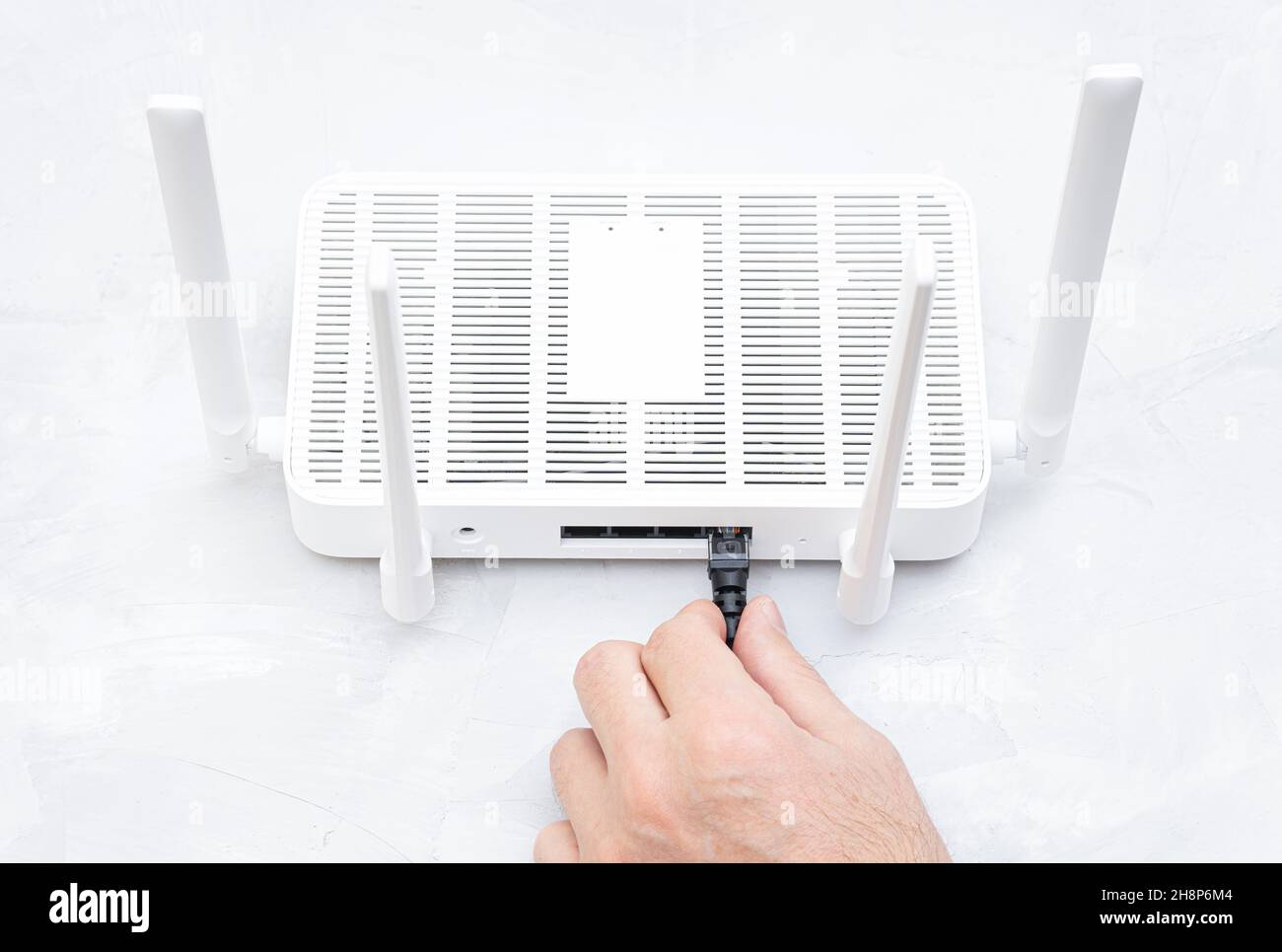 Male hand plugging internet cable into the router Stock Photo - Alamy