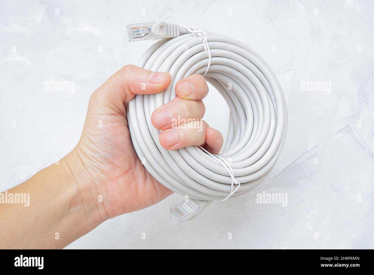 Hand holding a roll of ethernet cable against a grey background Stock ...