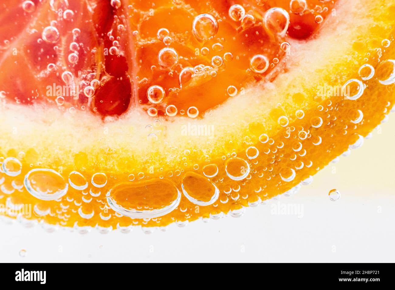 Grapefruit close-up in liquid with bubbles. Slice of blood red ripe ...