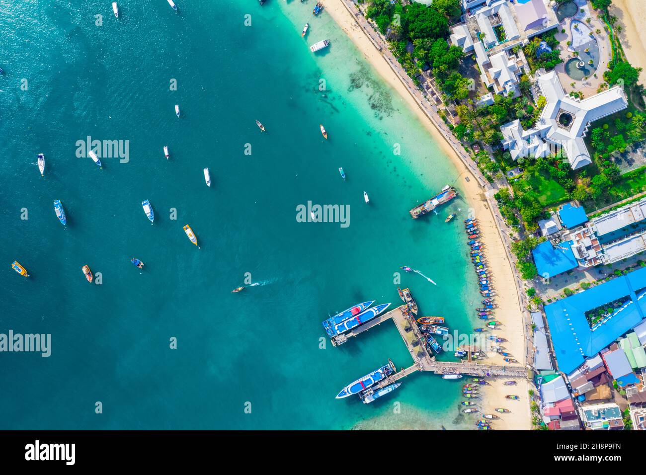 Flying above busy tropical island port filled with boats and ferries ...