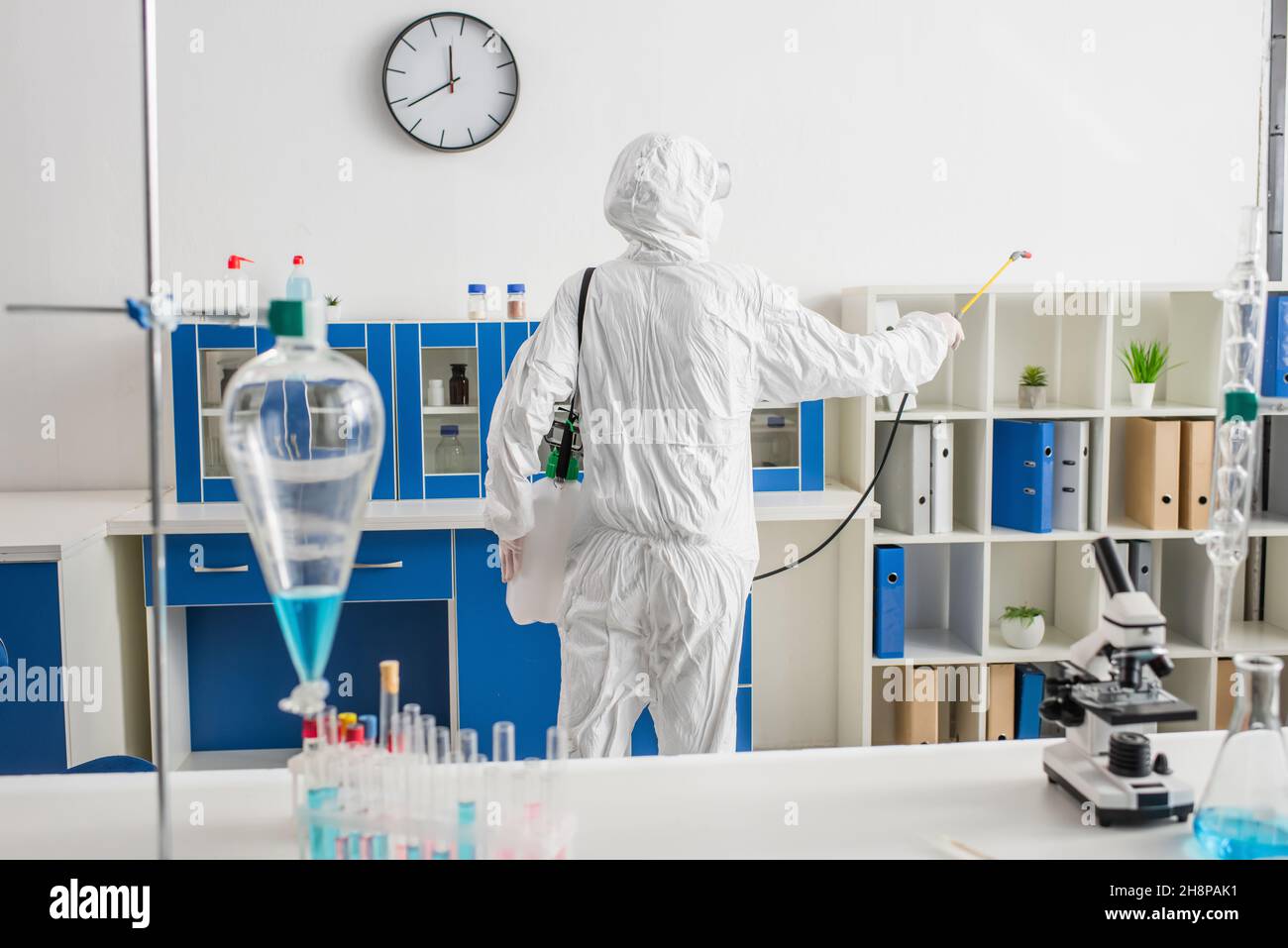 back view of doctor in hazmat suit making disinfection of laboratory ...