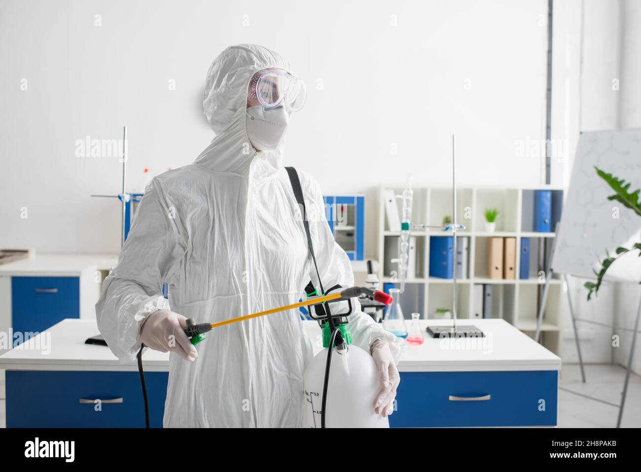 doctor in hazmat suit holding sprayer while making disinfection of ...