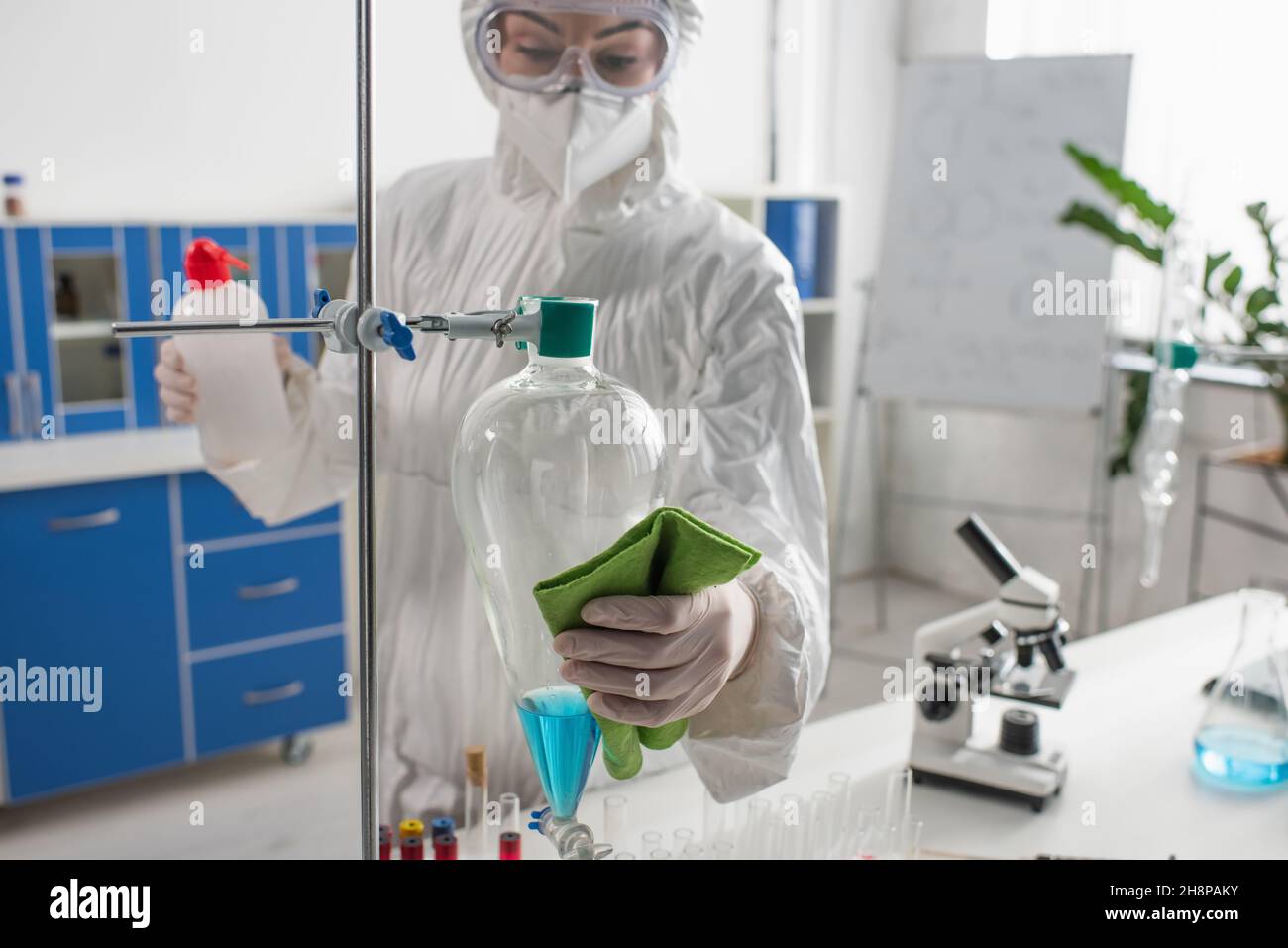 scientist in hazmat suit wiping flask with rag while making ...