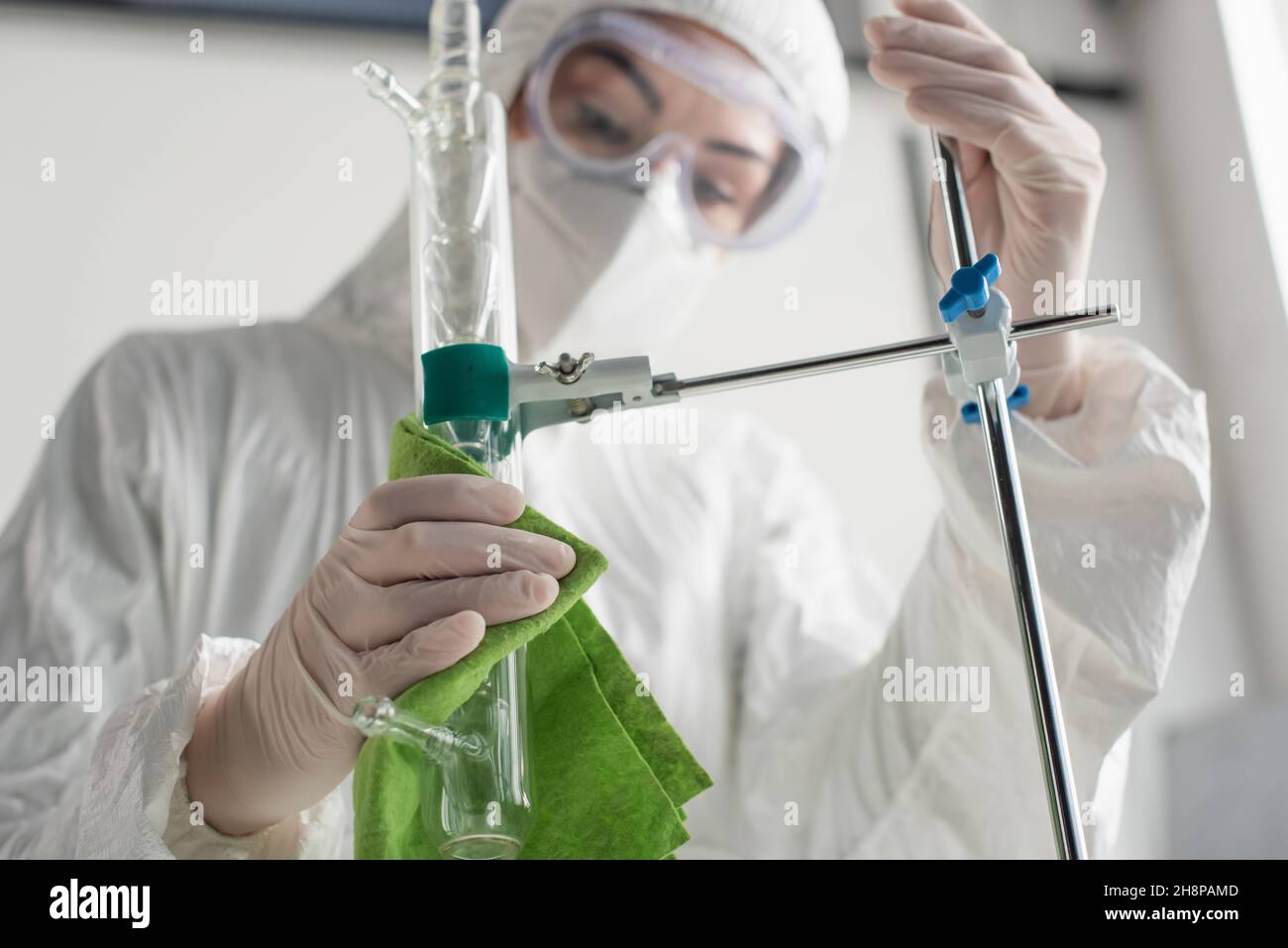 blurred scientist in latex gloves cleaning tripod with flask in ...