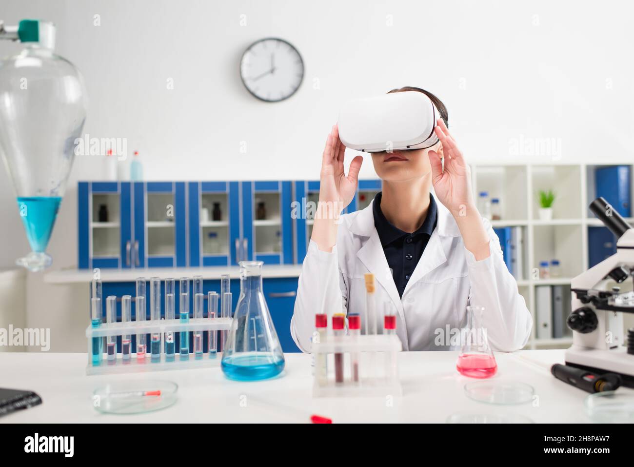 Scientist in vr headset near microscope and test tubes with blood ...