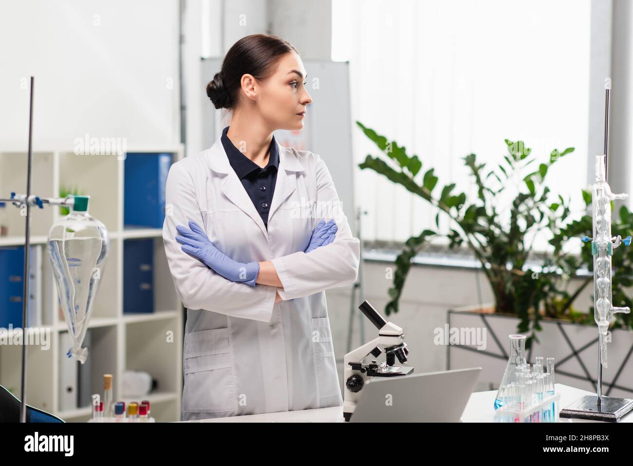 Side view of scientist in white coat standing near equipment on working ...