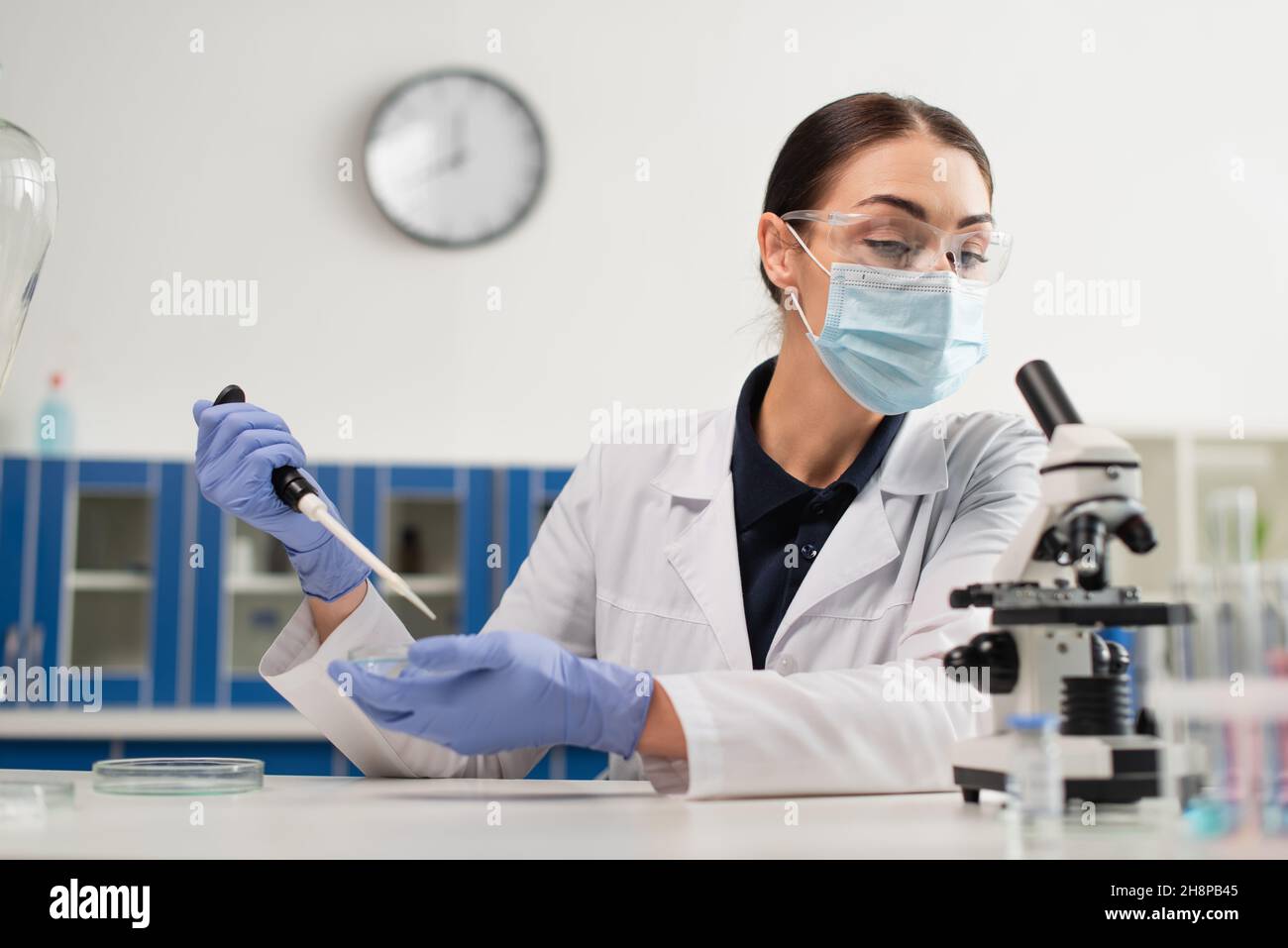 Scientist in goggles and latex gloves working with electronic pipette ...
